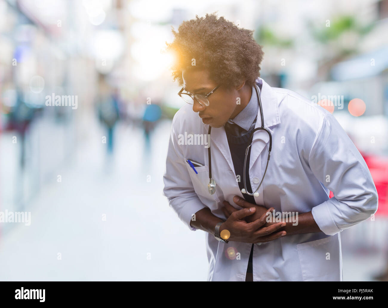 Afro american doctor man over isolated background with hand on stomach ...