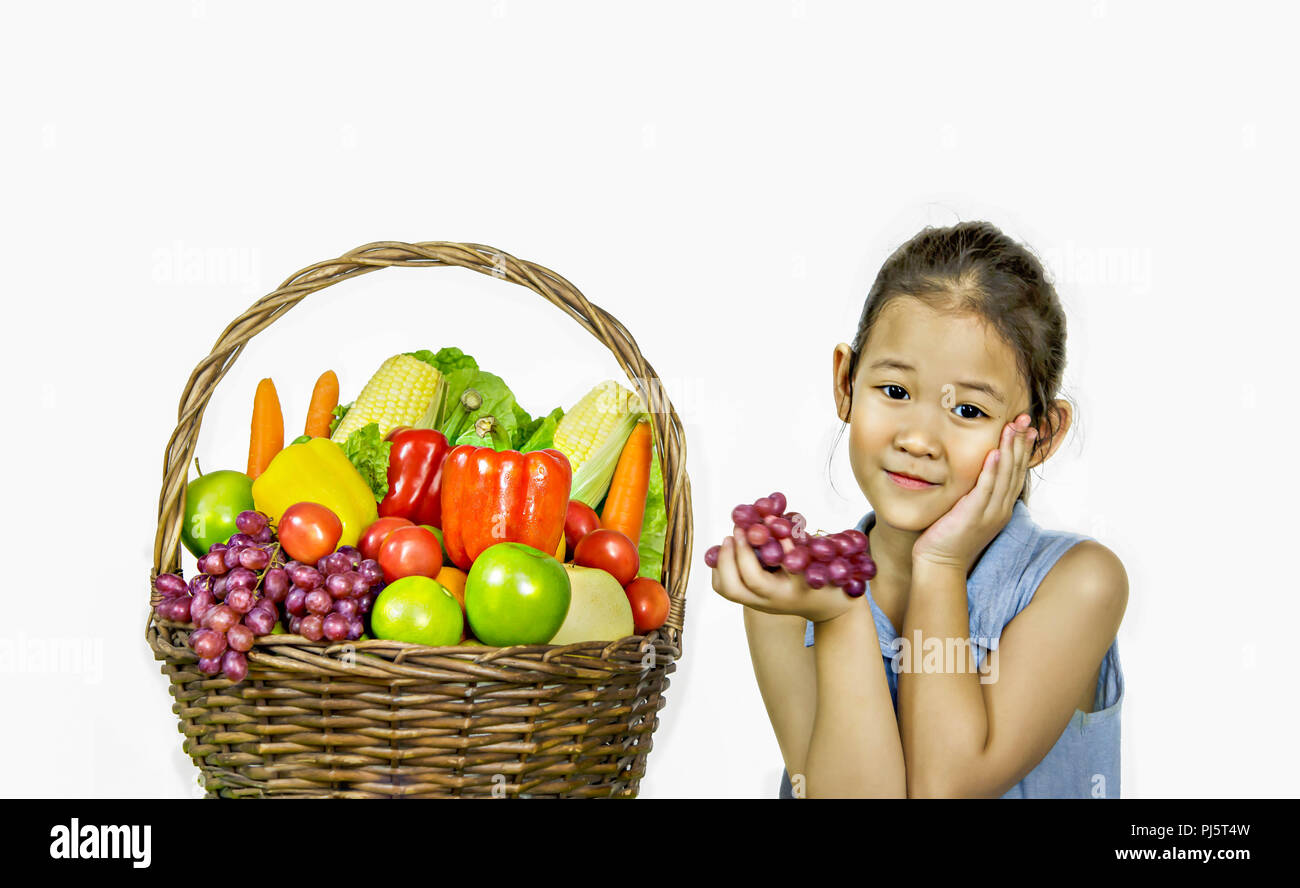 Smiling asian little girl with fruits and vegetables in basket over ...