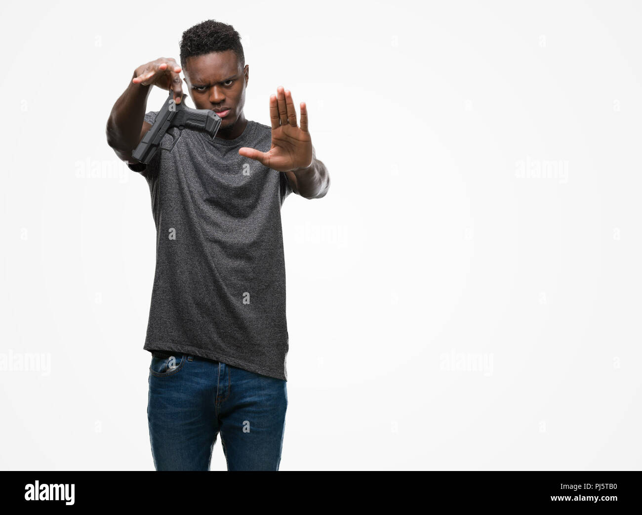 Young african american man holding a gun with open hand doing stop sign ...