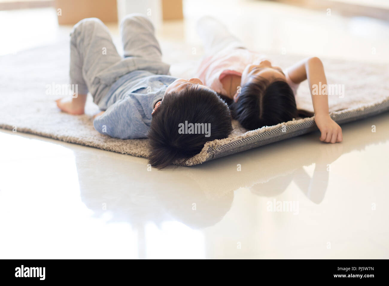 Cute children lying on carpet in new house Stock Photo - Alamy