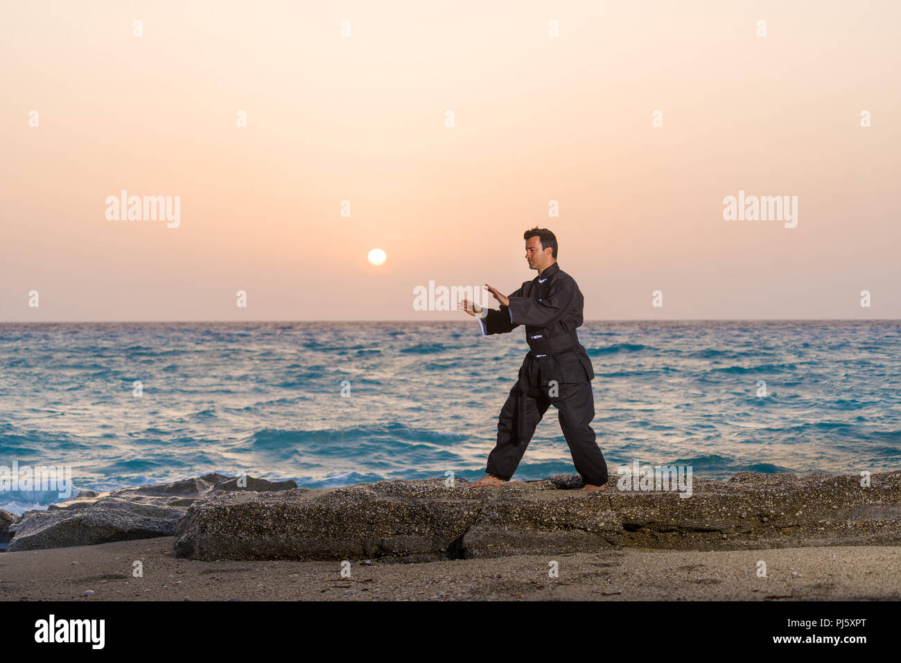 man performs tai chi moves agains sunset at the beach Stock Photo - Alamy