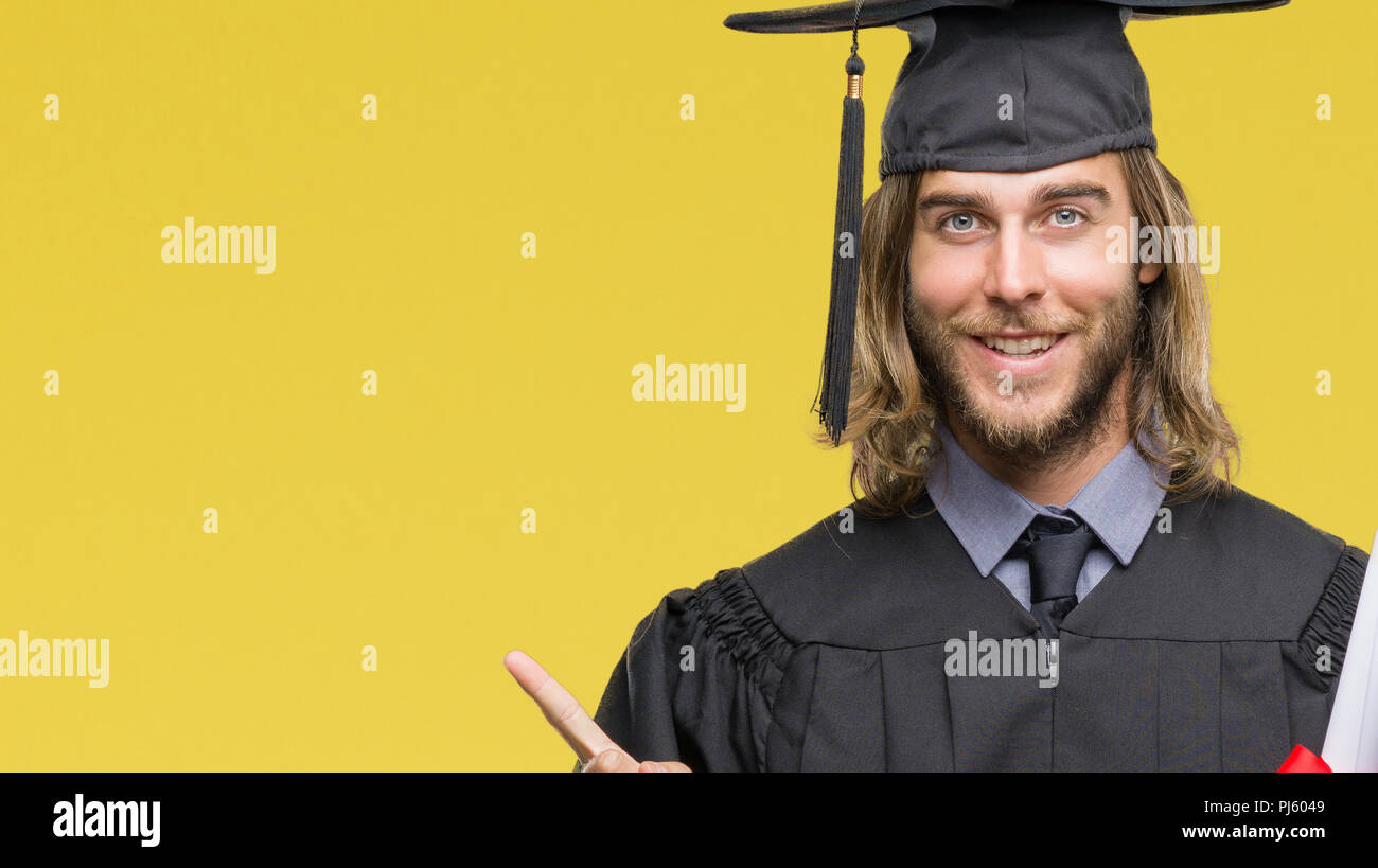 Young handsome graduate man with long hair holding degree over isolated ...