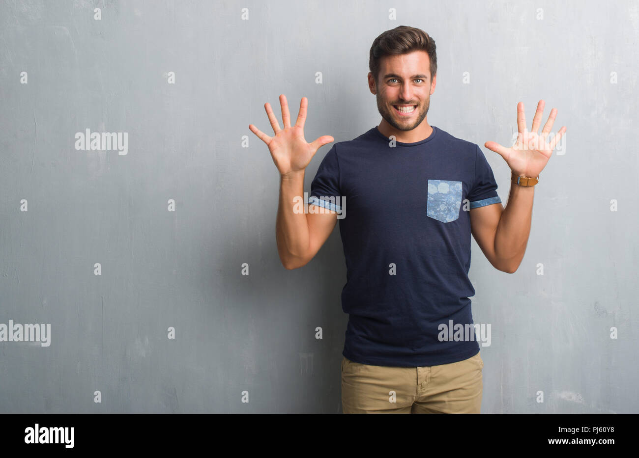 Handsome young man over grey grunge wall showing and pointing up with ...