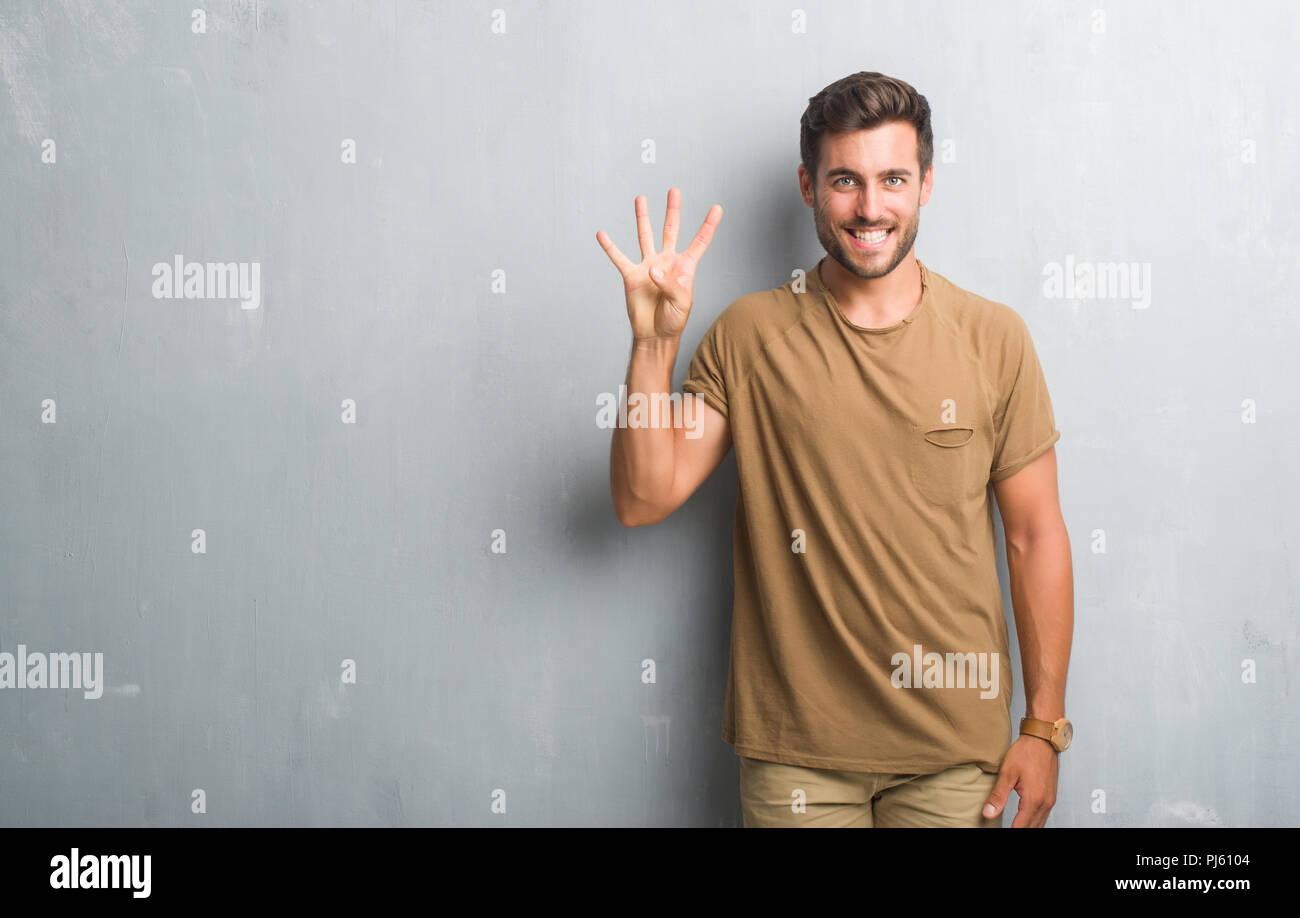 Handsome young man over grey grunge wall showing and pointing up with ...