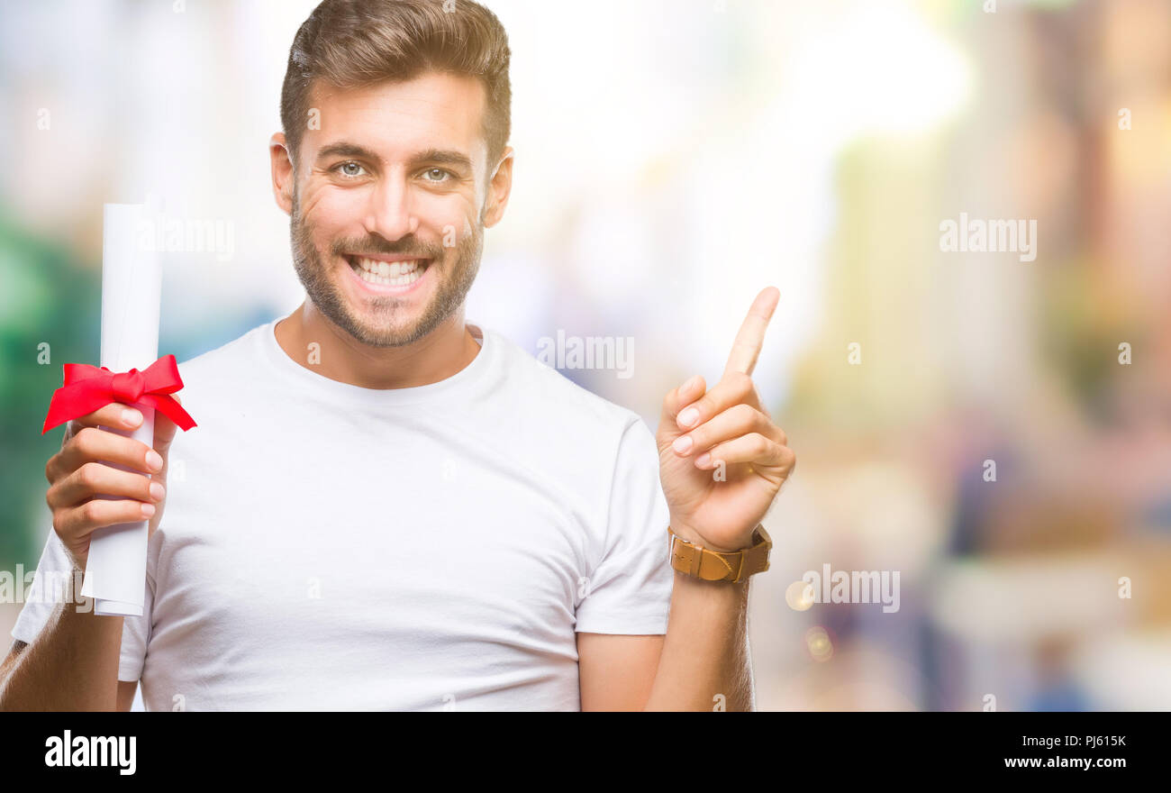 Young handsome man holding degree over isolated background very happy ...