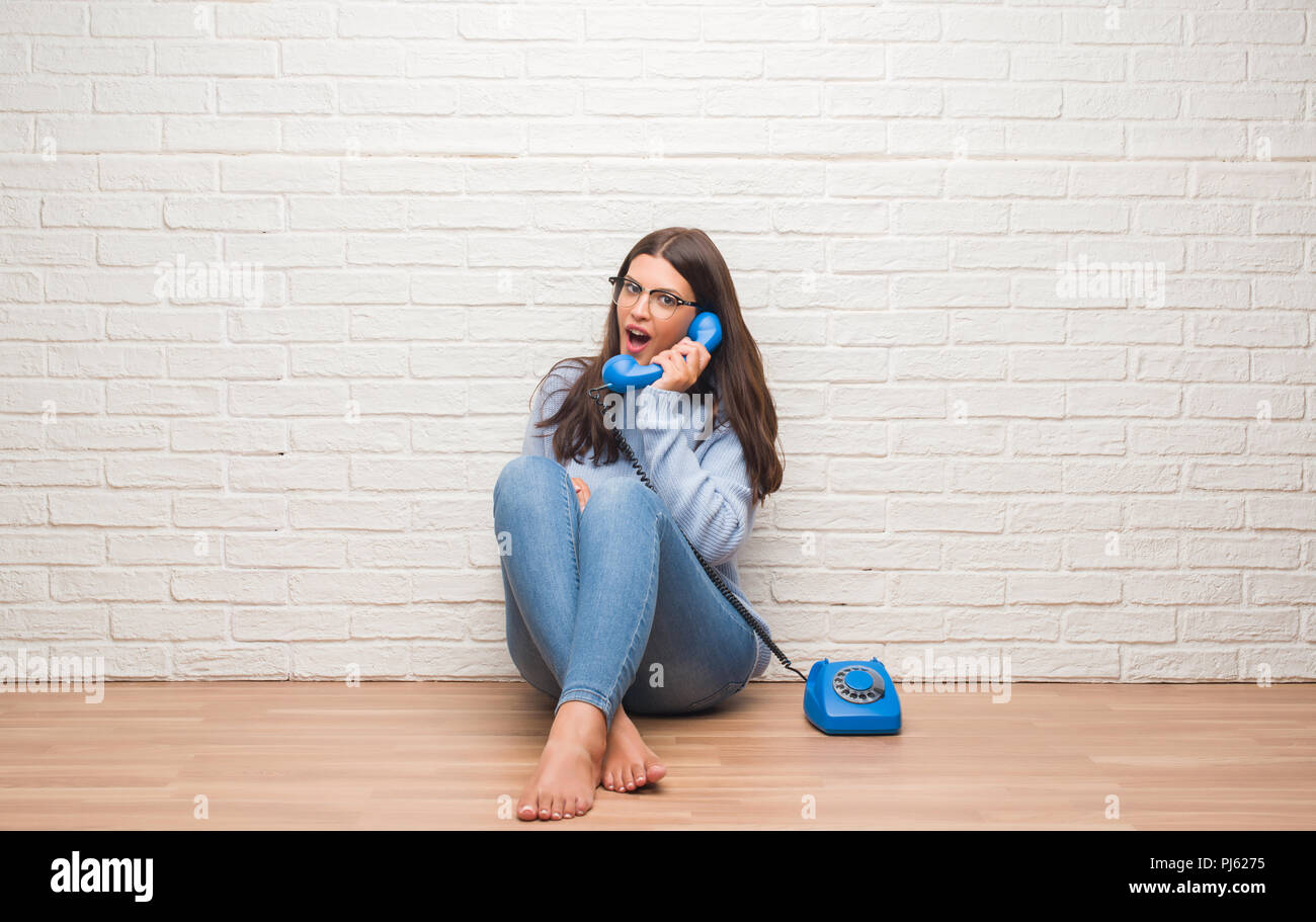 Young brunette woman sitting on the floor calling on vintage telephone ...