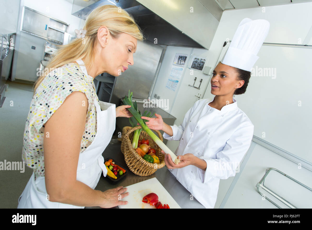 positive female chefs posing with plate of salad and cheese Stock Photo ...