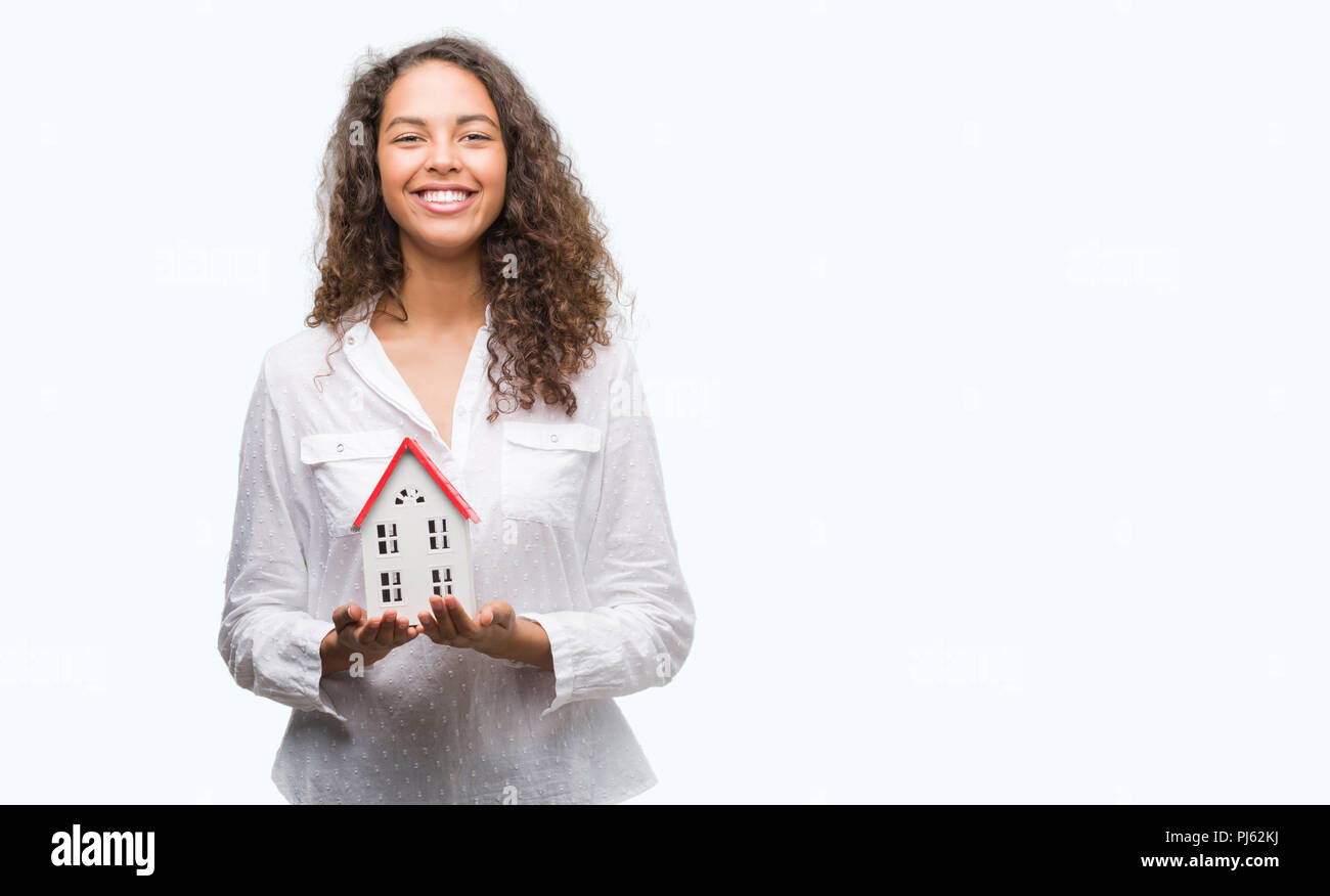 Young hispanic real state agent woman holding small house with a happy ...