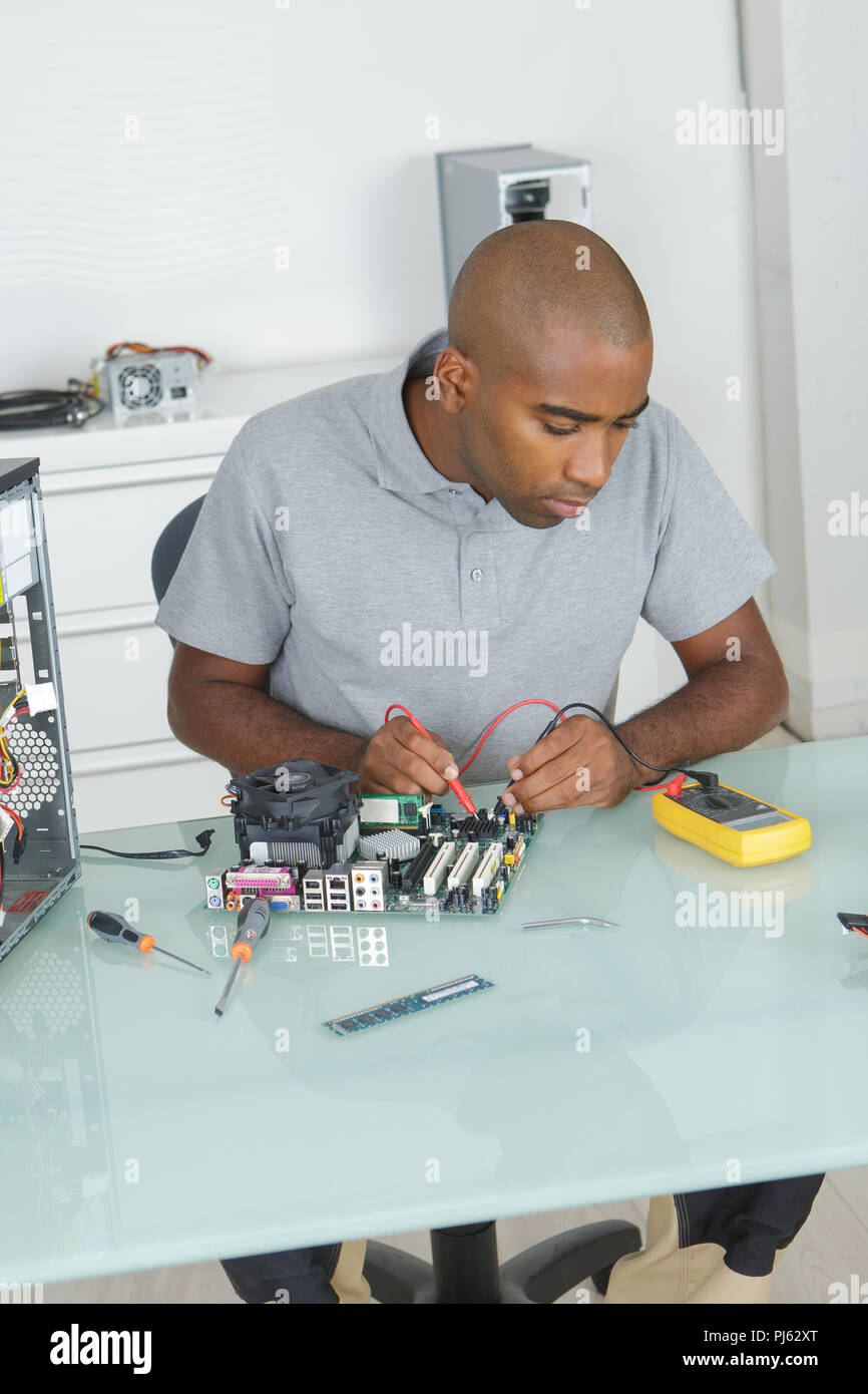 Technician testing computer component with multimeter Stock Photo - Alamy