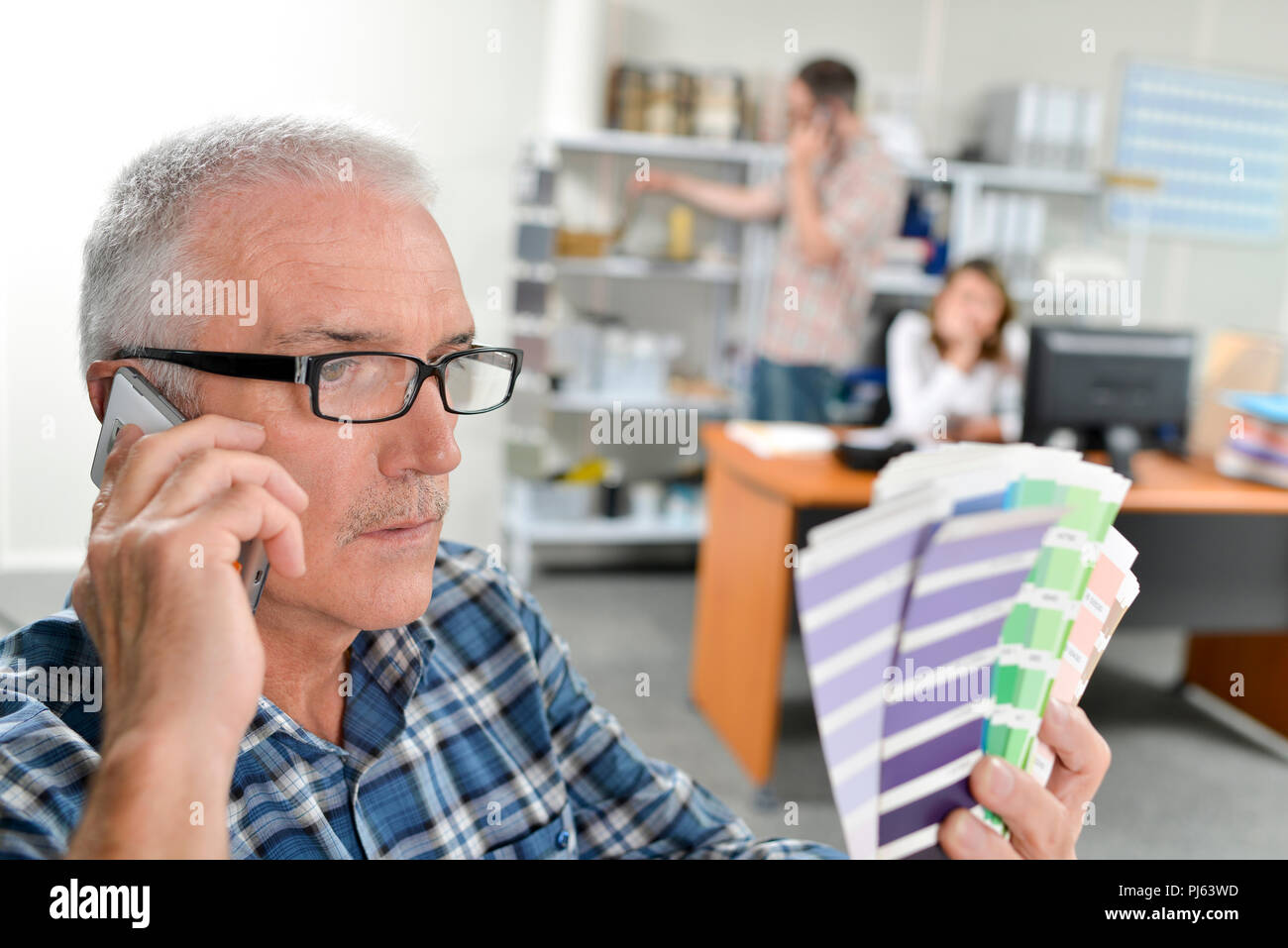 Man holding paint charts, talking on telephone Stock Photo - Alamy
