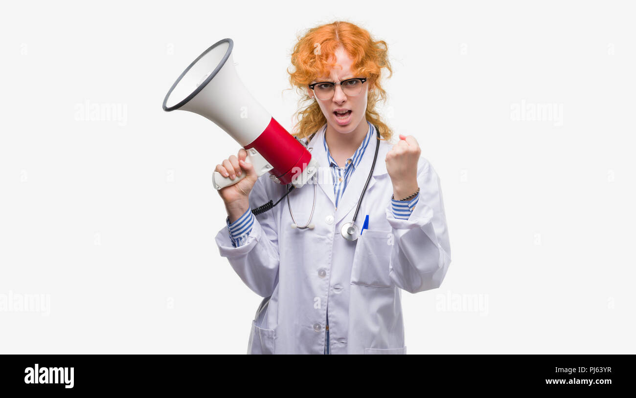 Young redhead doctor woman holding megaphone annoyed and frustrated ...