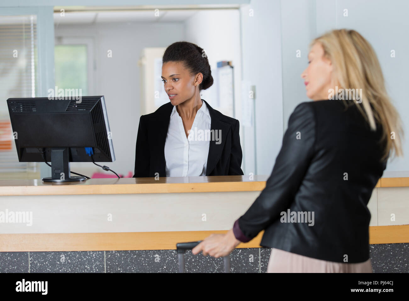 friendly hotel receptionist handing over key to customer Stock Photo ...