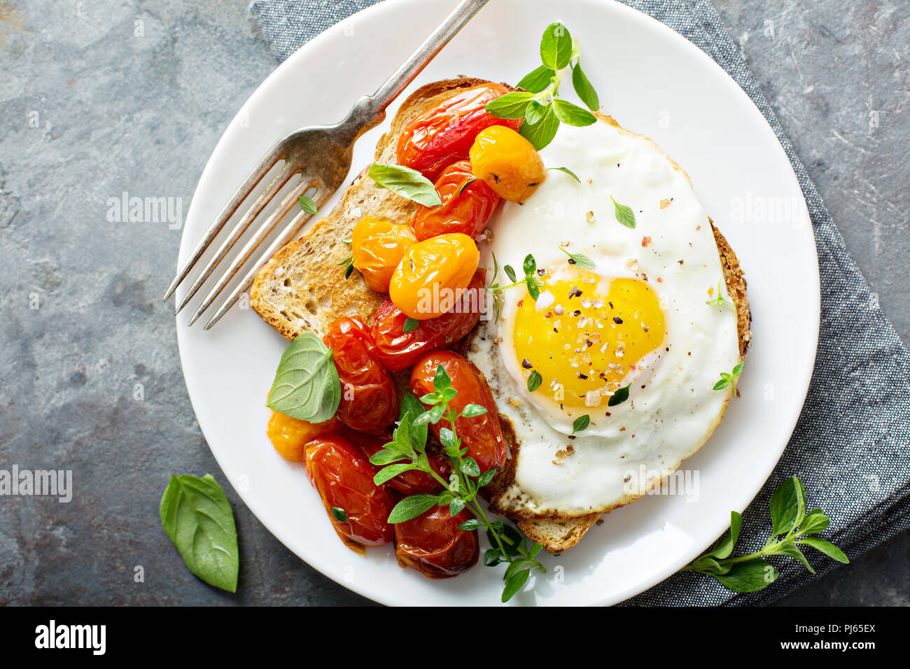 Multigrain toast with fried egg, fresh herbs and roasted tomatoes Stock ...