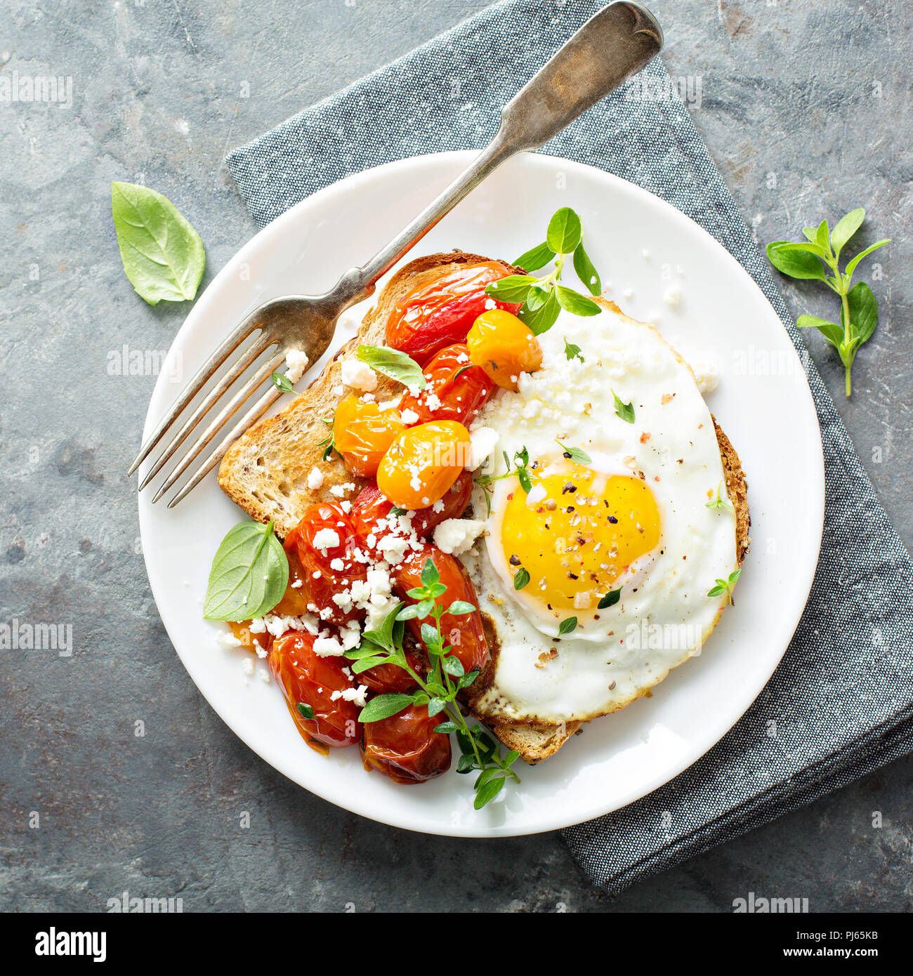 Multigrain toast with fried egg, fresh herbs and roasted tomatoes Stock ...
