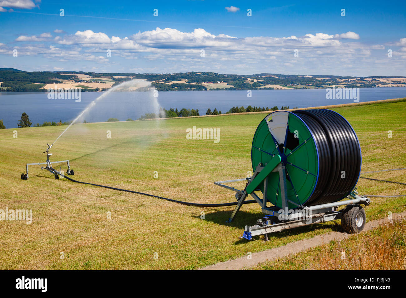 Travelling sprinkler with hose reel irrigation machine spaying water ...