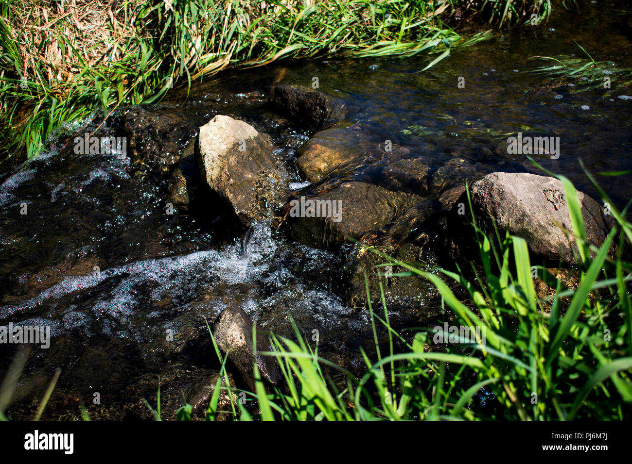 Natural stone dam in flowing stream Stock Photo - Alamy