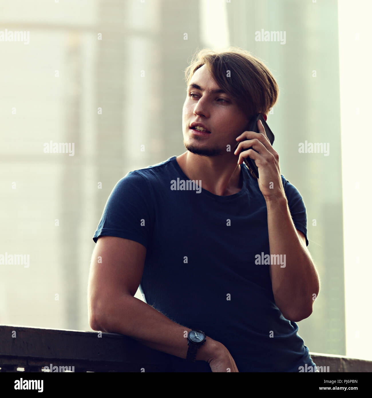 Young thinking casual man walking on the street and talking on mobile ...