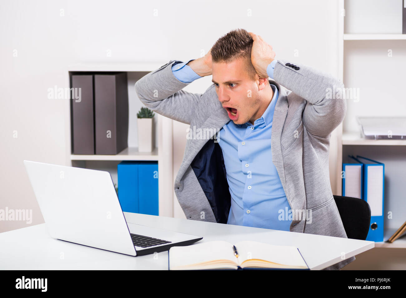 Businessman with laptop sitting at his office and he is in panic Stock ...
