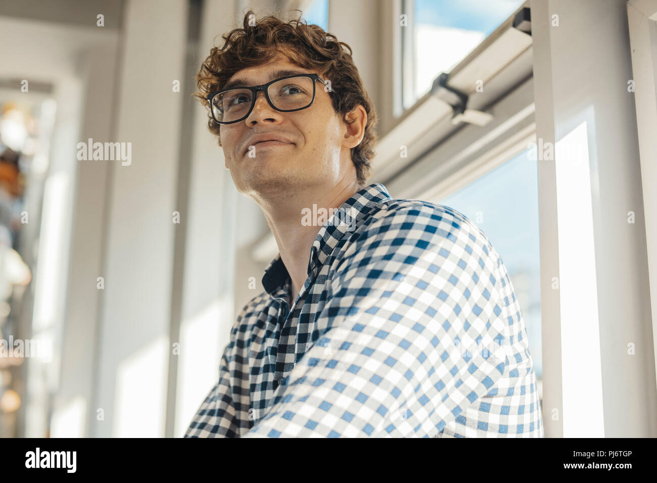 Close up of young man sitting next to big windows at metro station ...