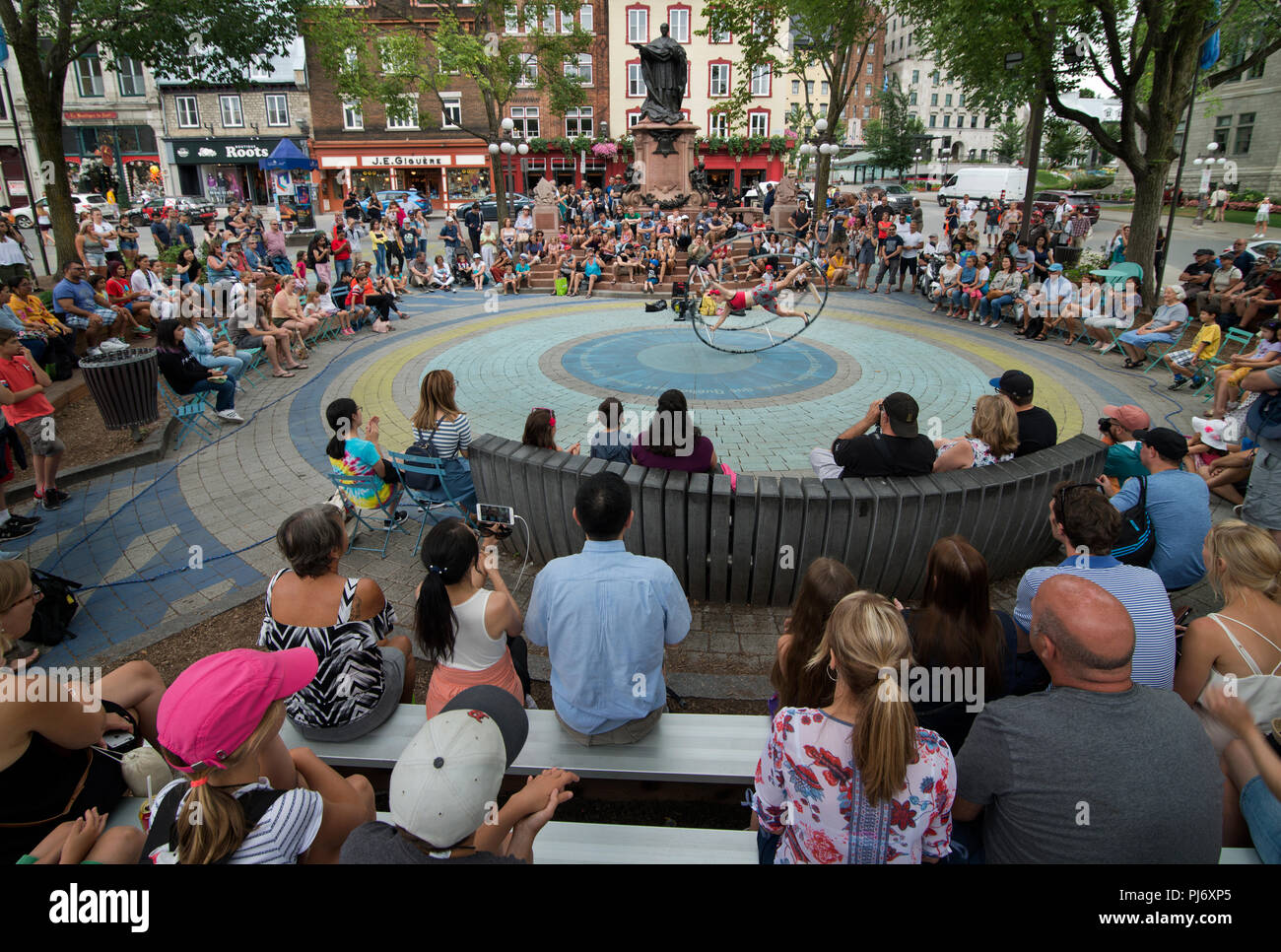 Street performer (Busker) preforming in a small park with a monument to ...