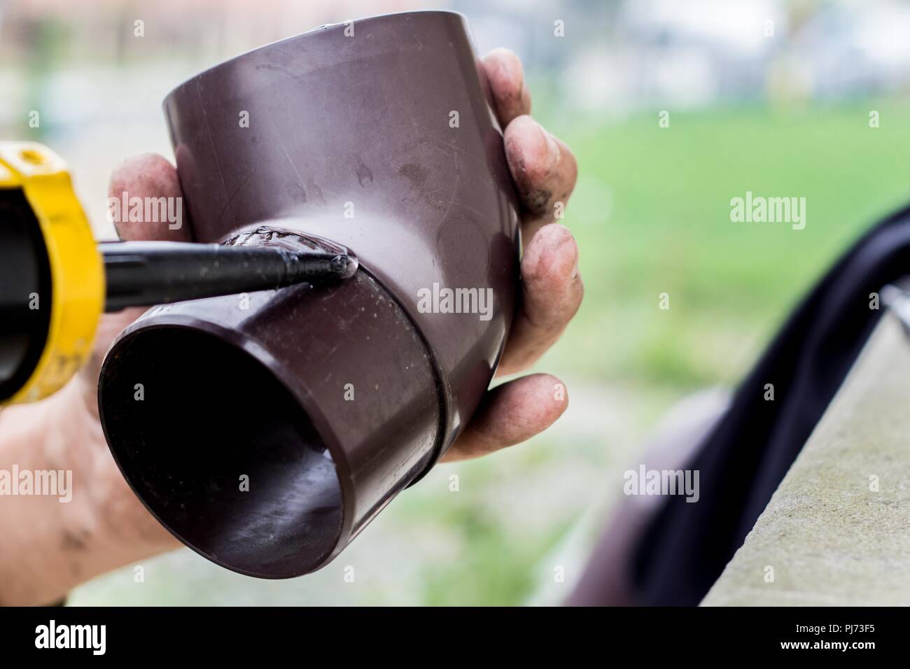men's hands lubricate the gutter with a sealing agent Stock Photo - Alamy