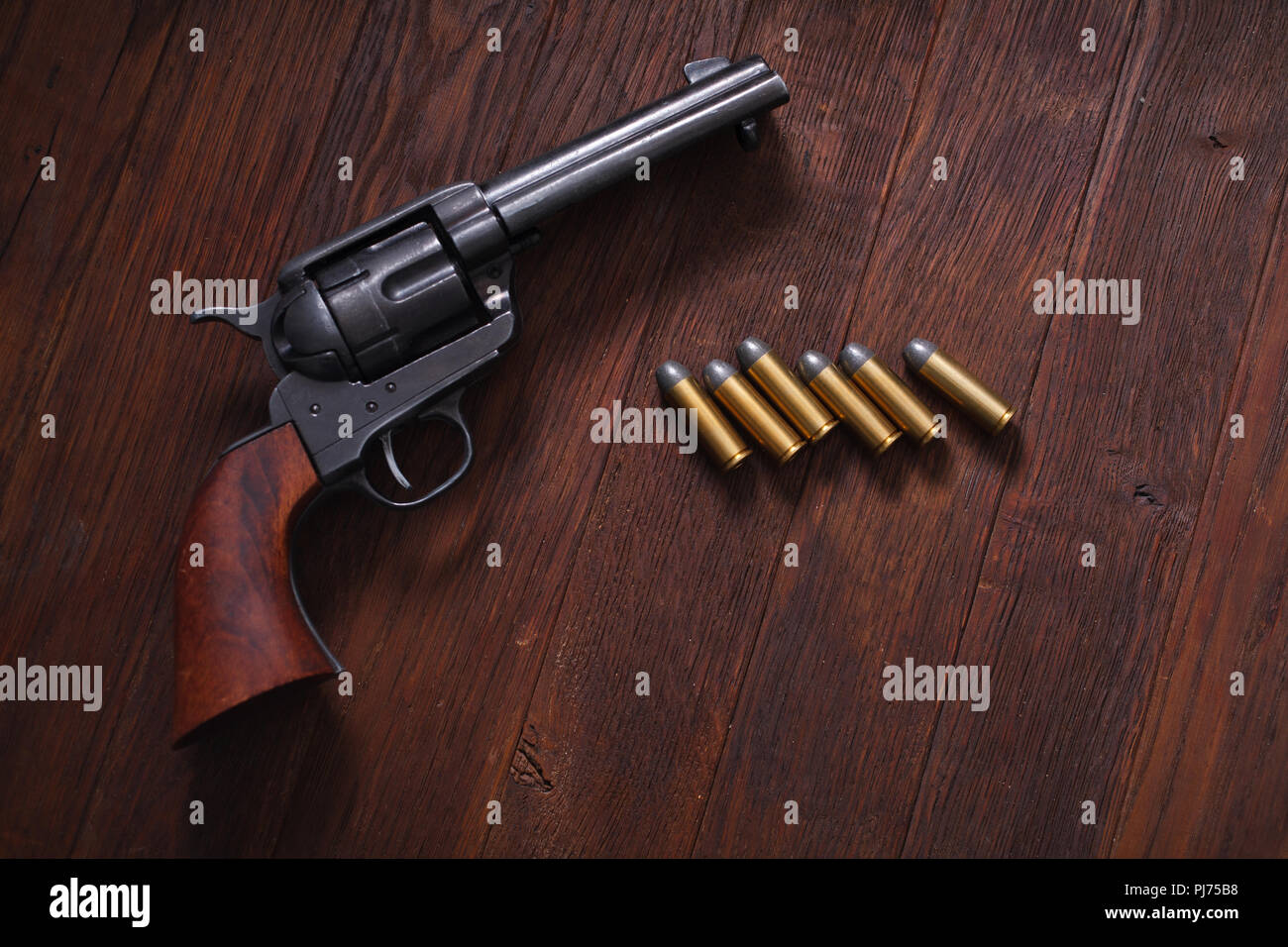 Old revolver with cartridges on wooden table Stock Photo - Alamy