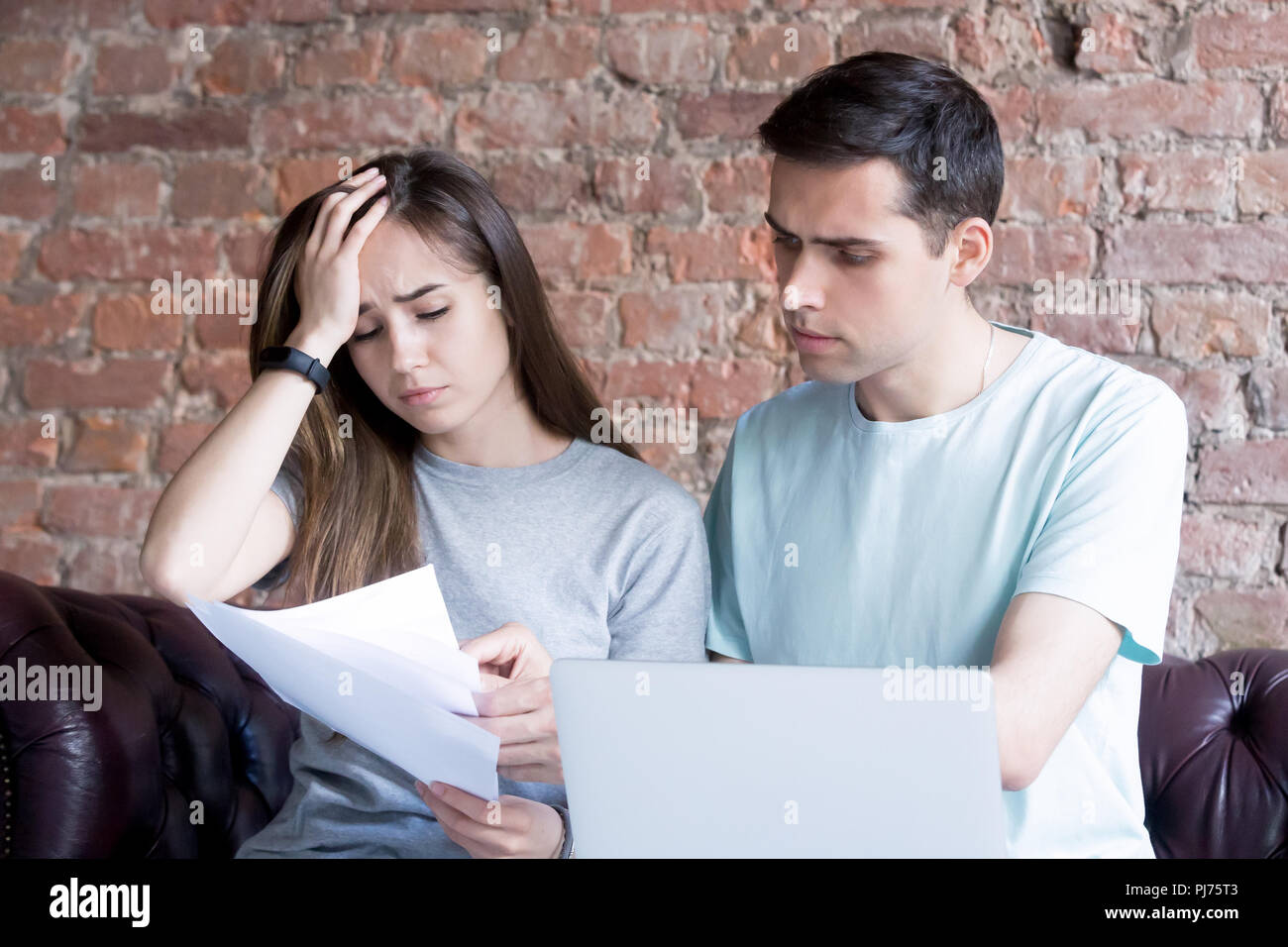 Stressed young couple sitting on couch at home Stock Photo - Alamy