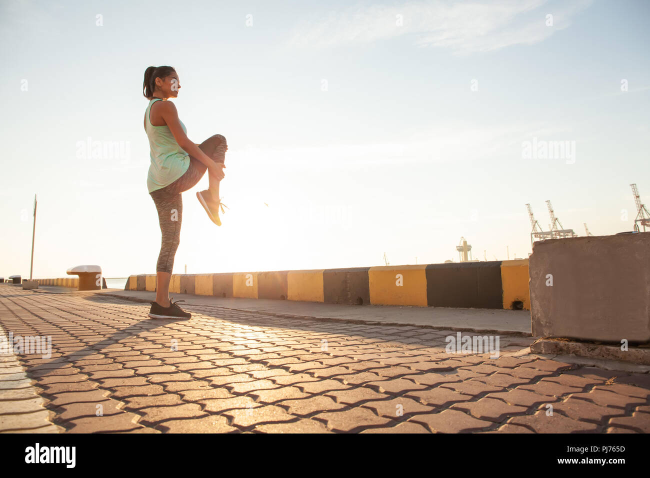 young fitness woman runner stretching legs before run on city Stock Photo - Alamy