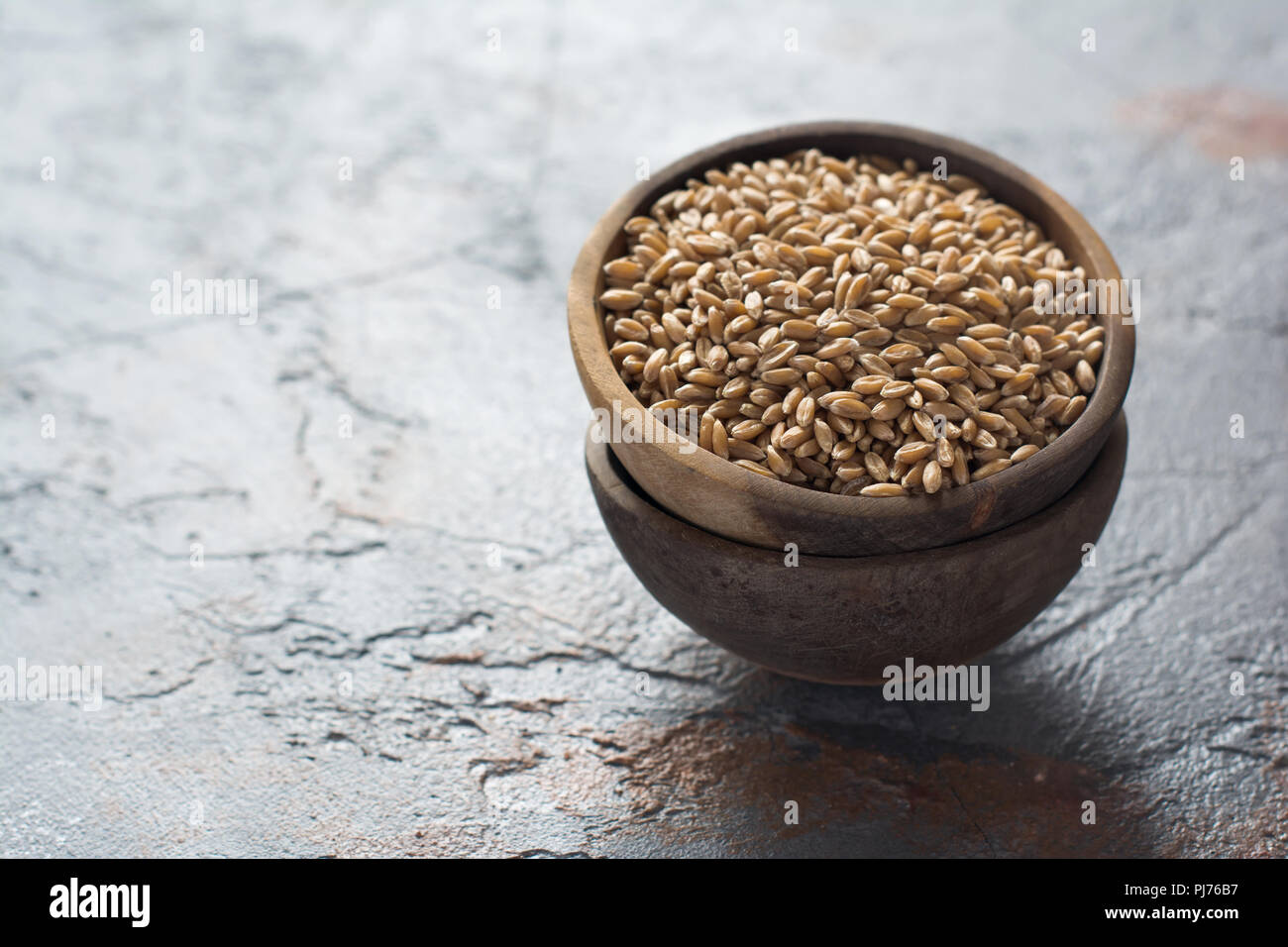 One of the ancient cereals, spelt on the dark grey stone table ...