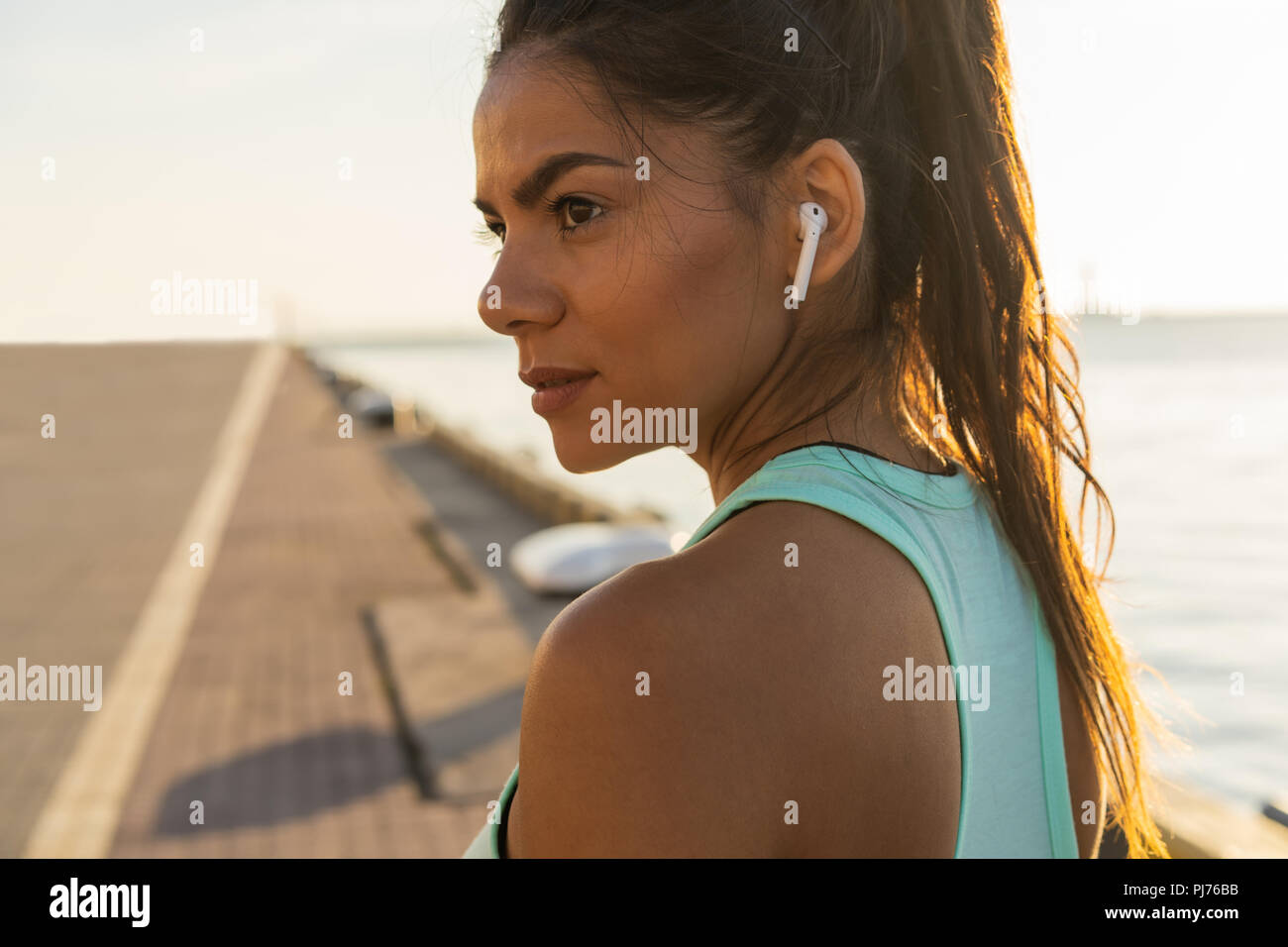 Tired fitness woman sweating taking a break listening to music on phone ...