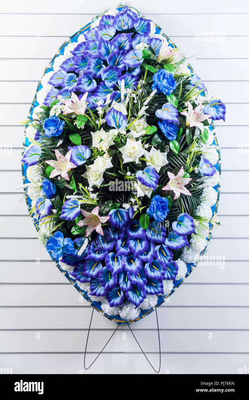 Luxury funeral wreath with blue and white flowers on a white striped ...