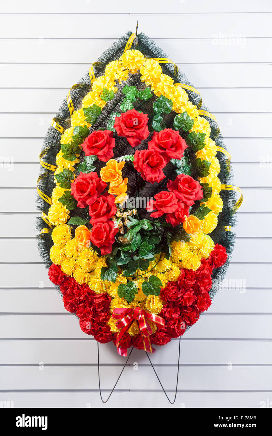 Luxury funeral wreath with red and yellow flowers on a white striped ...