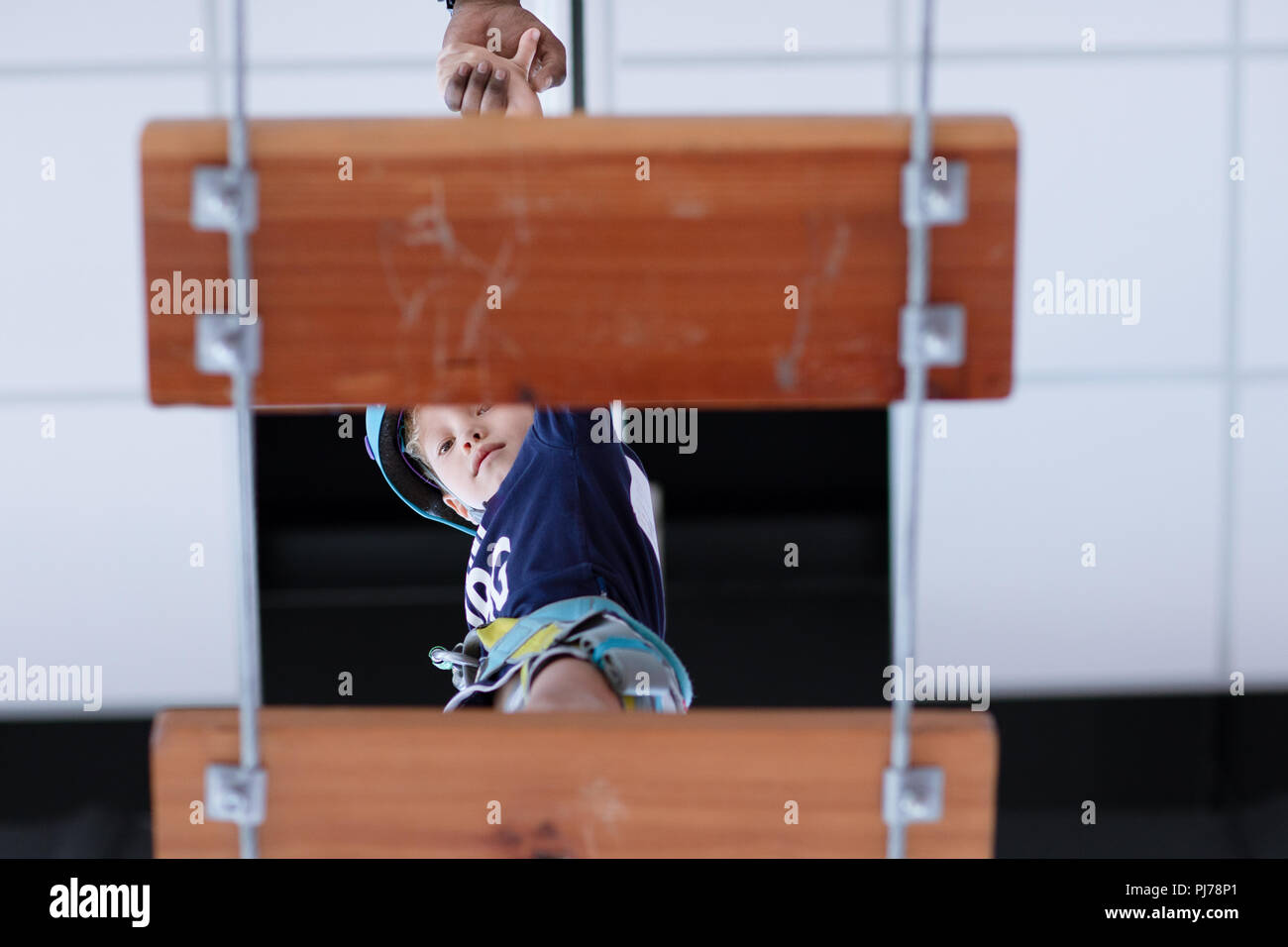 Young boy being helped to cross a bridge at the high rope course Stock ...