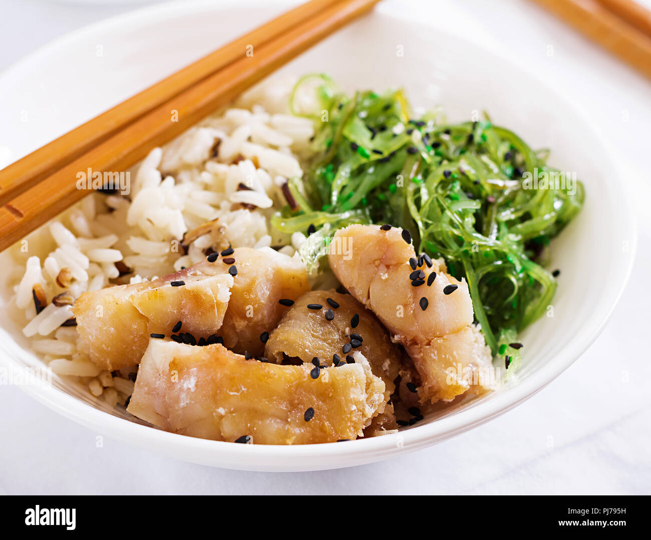 Japanese food. Bowl of rice, boiled white fish and wakame chuka or ...