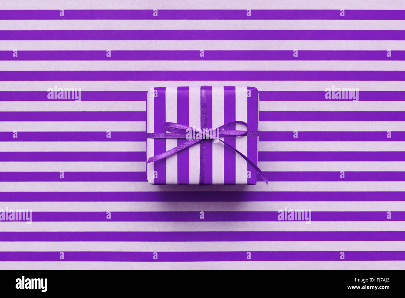 Purple gift box on violet striped wrapping paper. Minimal design ...