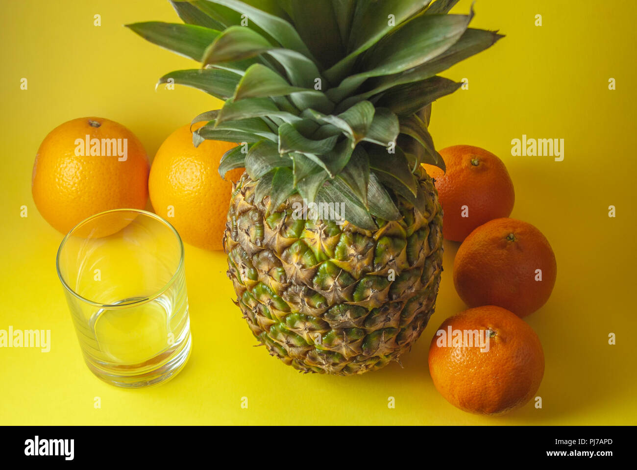 Single pineapple isolated on yellow background with empty glass and ...