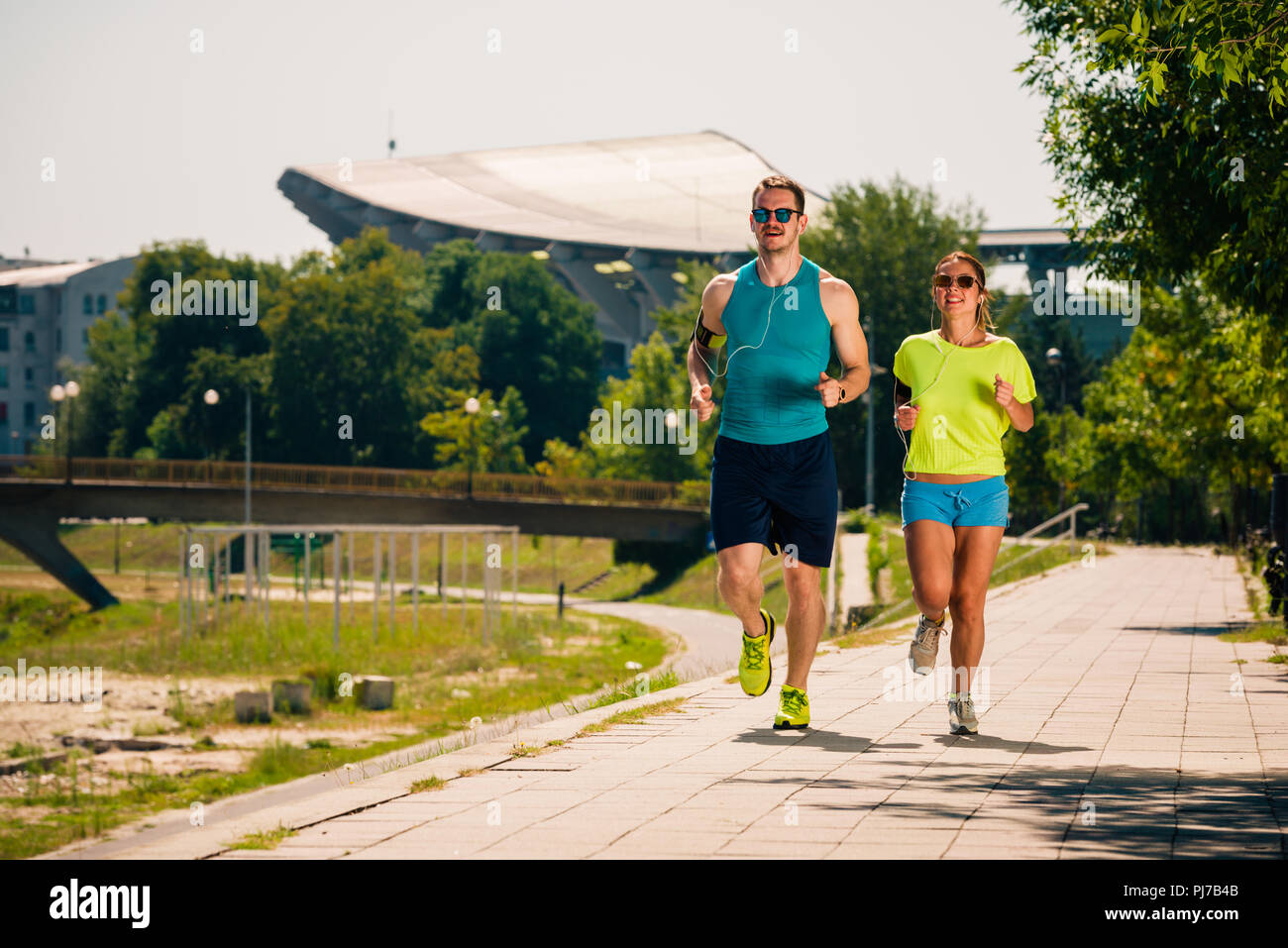 Two athletic people running through the riverside Stock Photo - Alamy