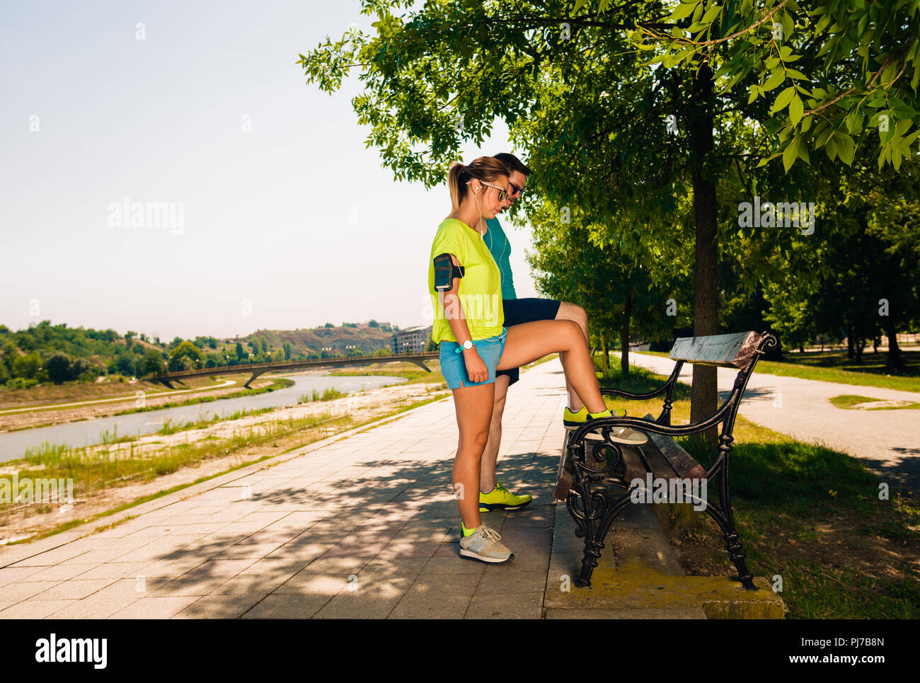 Athletic young couple doing stretching legs exercises together on the ...