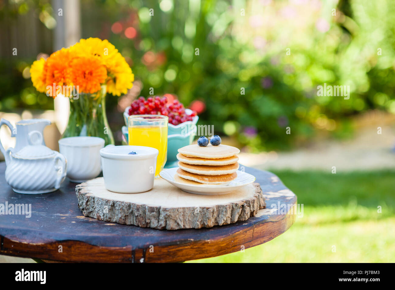 Breakfast in the garden: pancakes with yoghurt and berries on a rustic ...