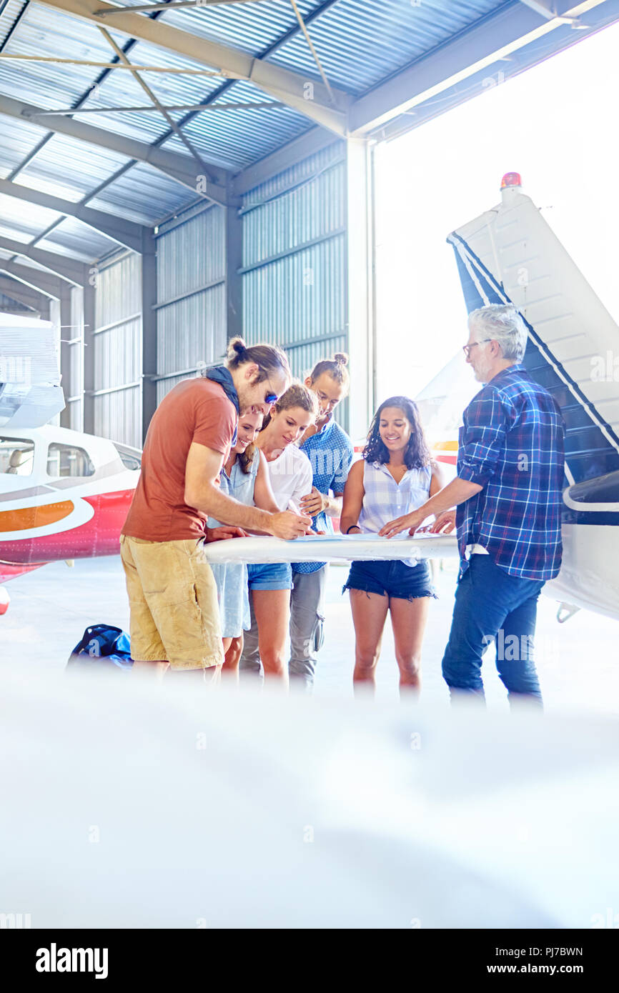 Friends planning trip at map in airplane hangar Stock Photo - Alamy