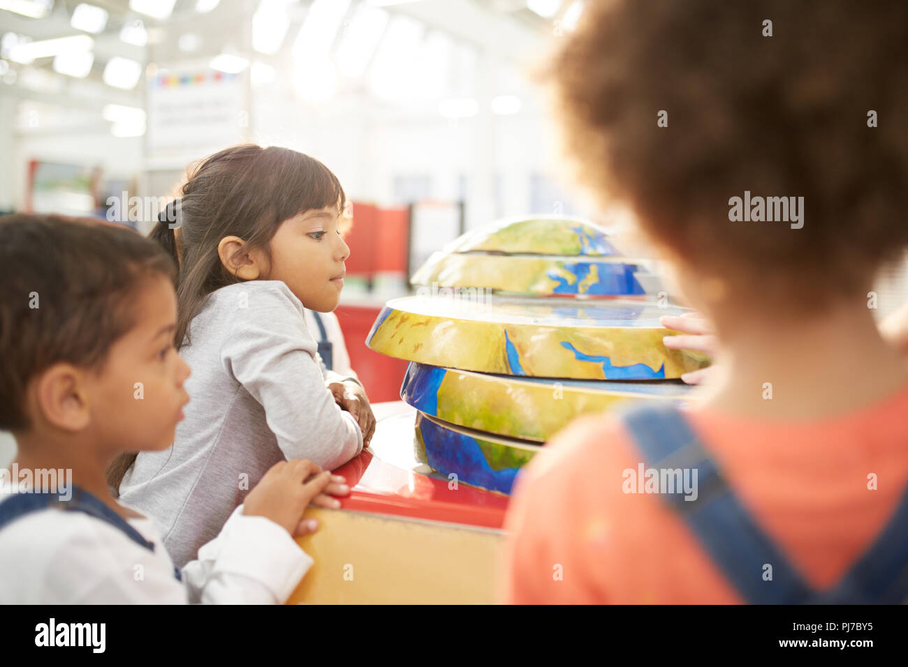 Curious kids watching interactive earth exhibit in science center Stock ...