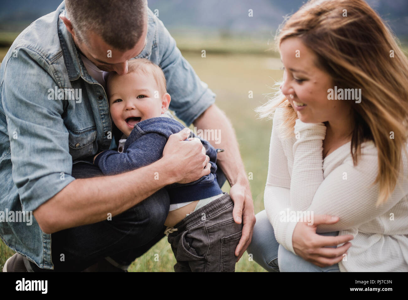 Parents hugging happy baby son Stock Photo - Alamy
