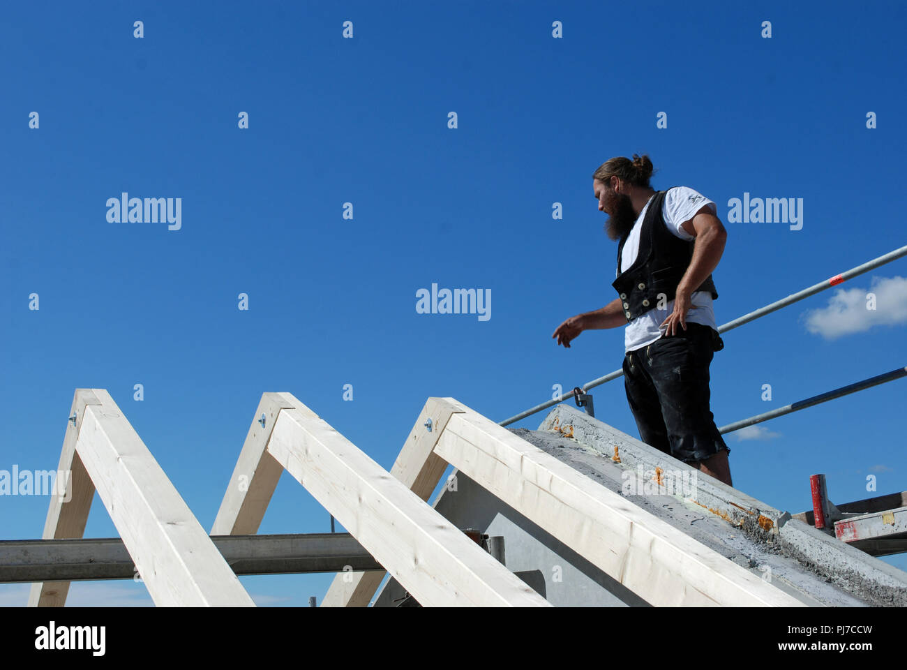 Carpenter in traditional work costume on roof of new house Stock Photo ...