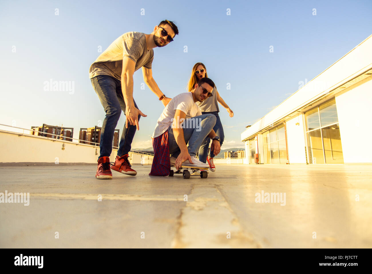 Group of friends having fun with longboard at sunset on rooftop Stock ...