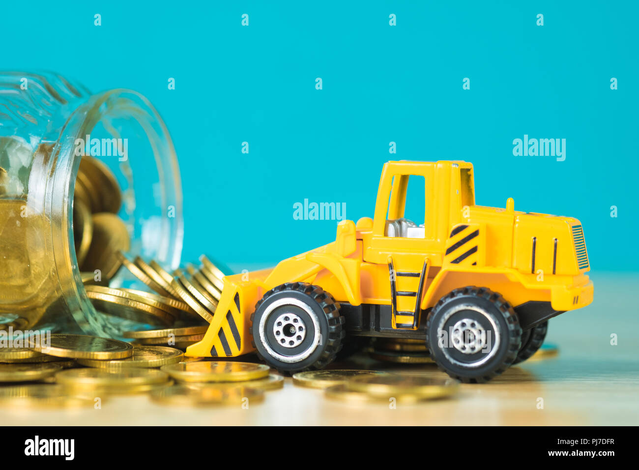 Mini bulldozer truck loading stack coin with pile of gold coin to glass ...