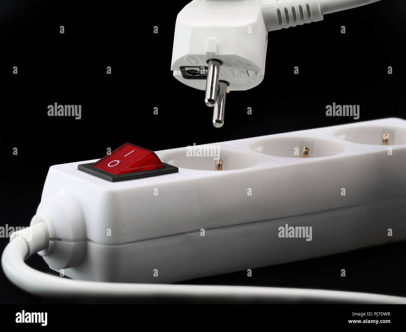 close up of power button and plug from a white power strip on black ...