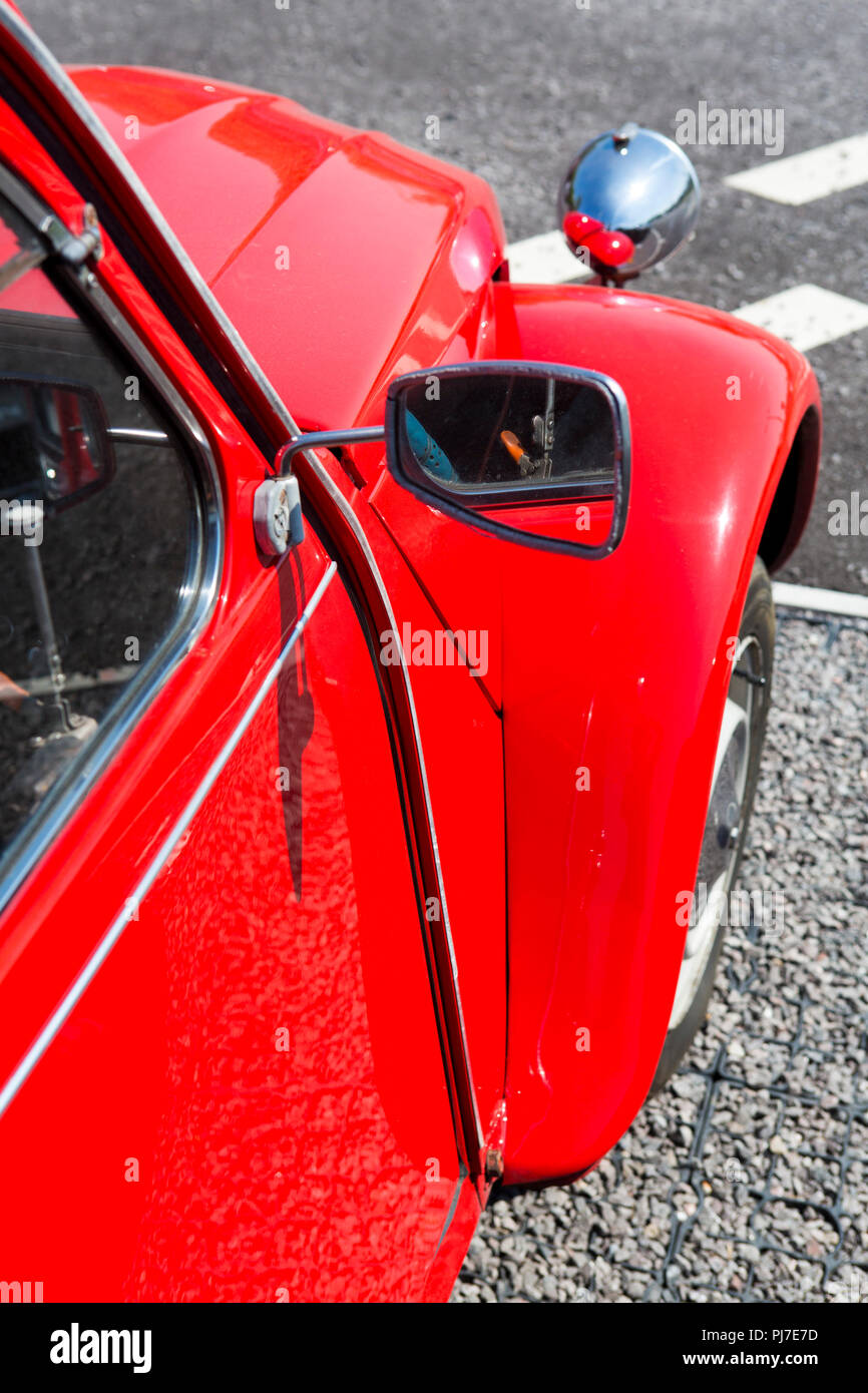 Detail of an old red Citroen 2CV car set aginst a deep blue summer sky ...