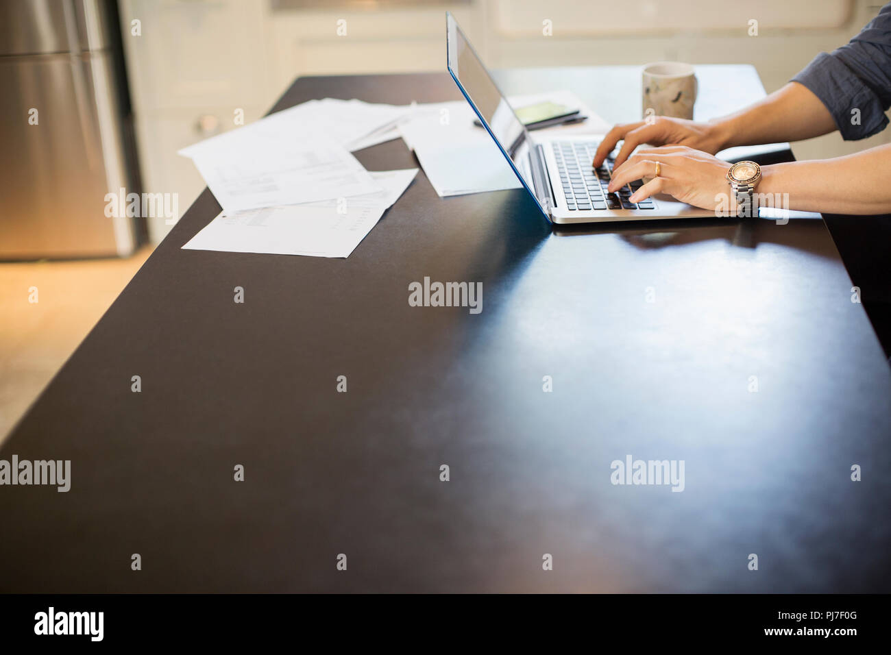 Man typing, working at laptop at dining table Stock Photo - Alamy