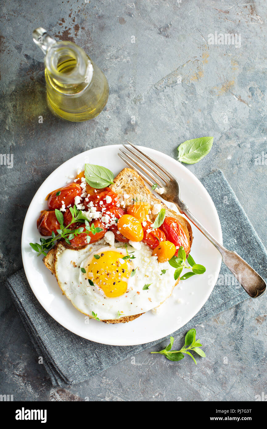 Multigrain toast with fried egg, fresh herbs and roasted tomatoes Stock ...