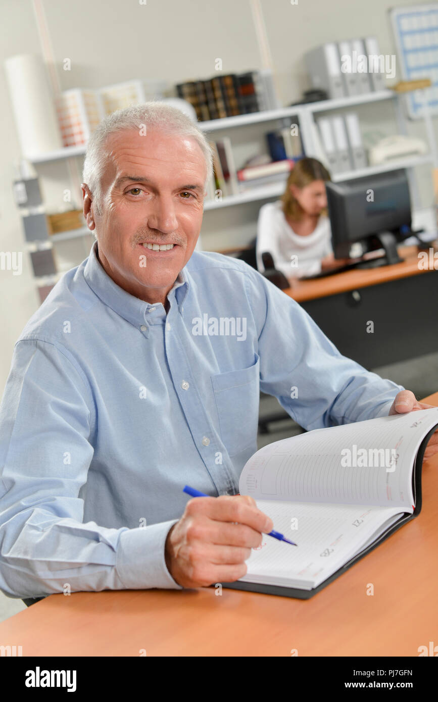 Man sat at desk with open diary Stock Photo - Alamy